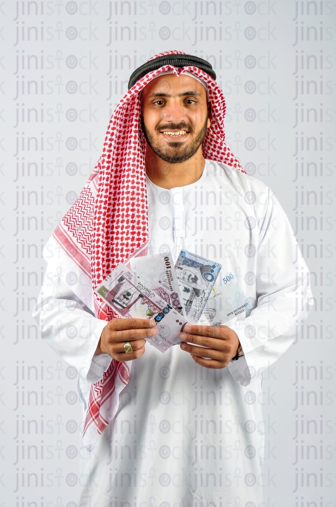 Saudi man holding Saudi Arabia riyals in his hands | Jini Stock