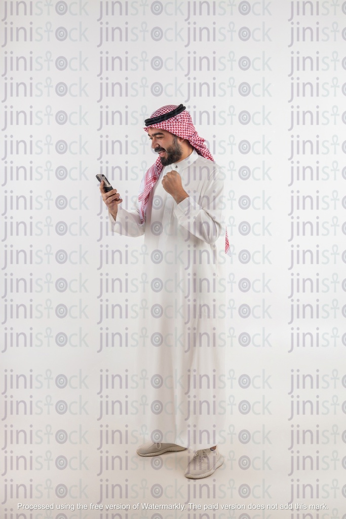 Khaliji man looking at his phone happy winning | Jini Stock