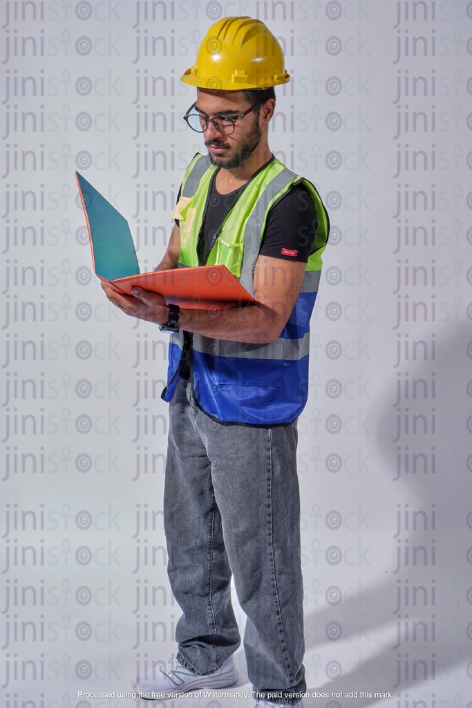 Egyptian engineer standing checking designs | Jini Stock