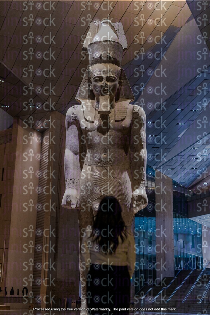 An Egyptian girl stands in front of the statue of Ramses II inside an ...
